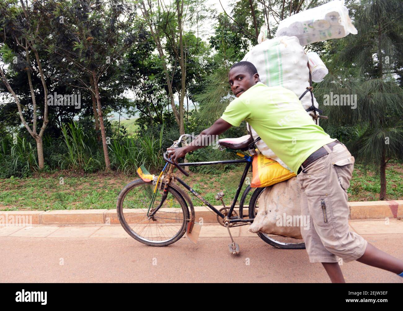 A Rwandan man pushing his loaded bicycle in rural Rwanda Stock Photo ...
