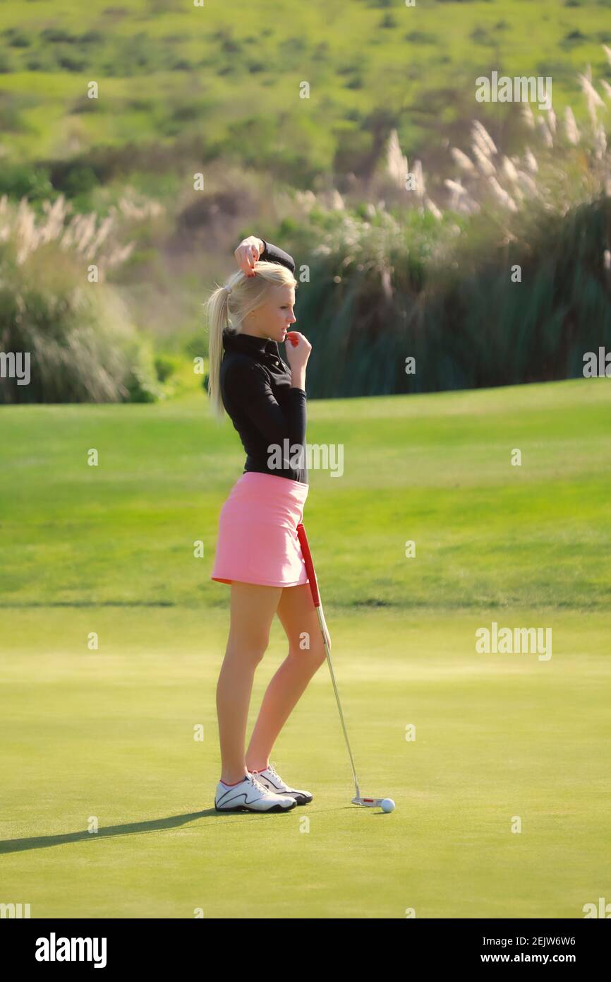 Young Female golfer tidy's up her hair prior to lining up a putt during a round in Southern ...