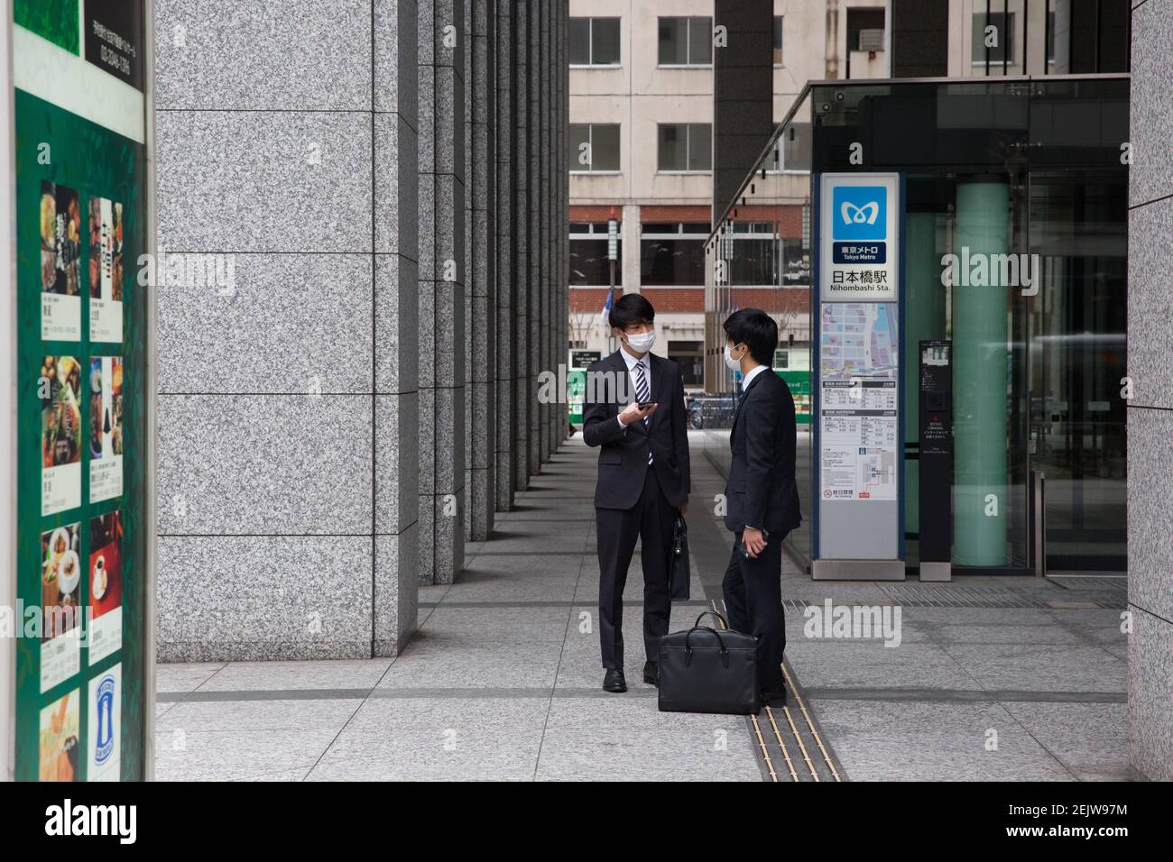 Businessmen having a conversation in front of Tokyo Metro Station ...