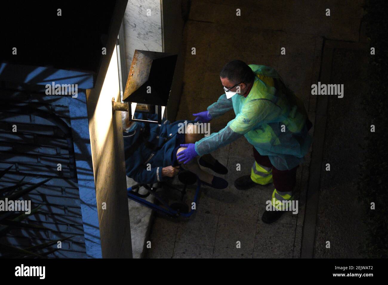Medical staff, wearing protective gear, move a patient, infected ...