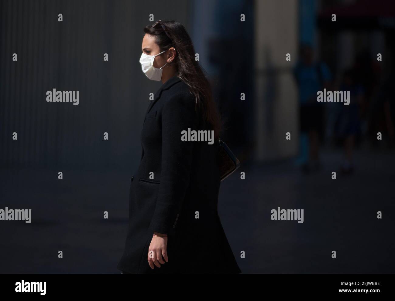 A woman wears a face mask as a precaution against the spread of ...