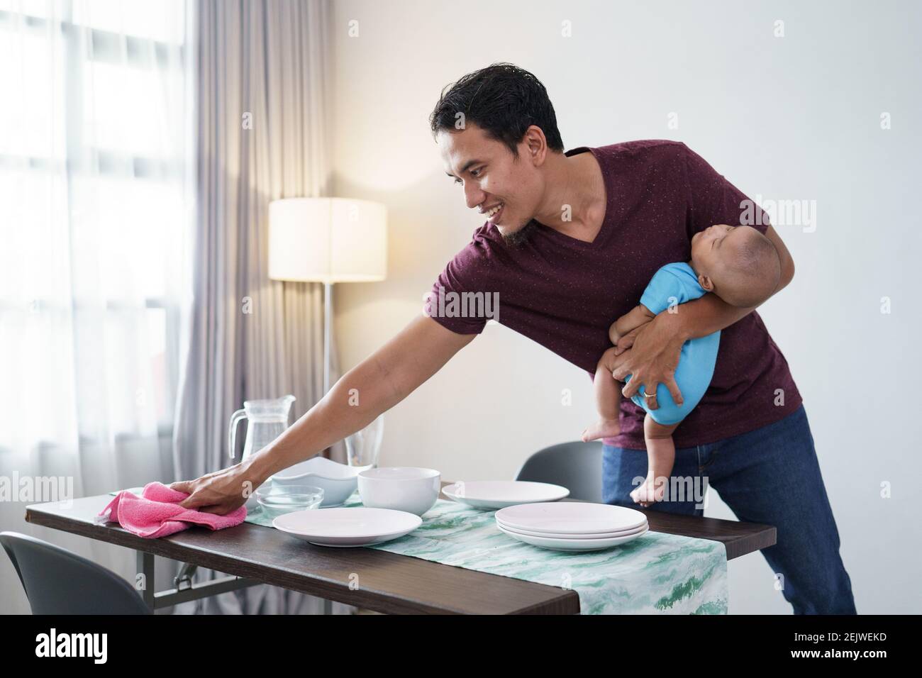 portrait of single father doing chores at home while carrying his baby ...
