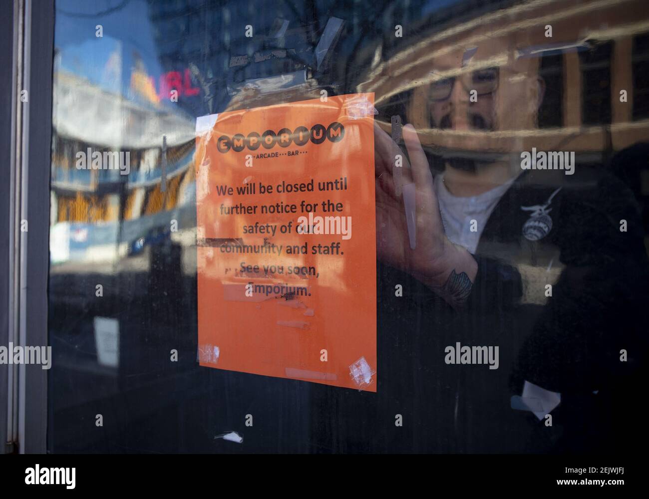 Rey Guzman hangs a sign at the Emporium bar in the West Loop on Sunday ...