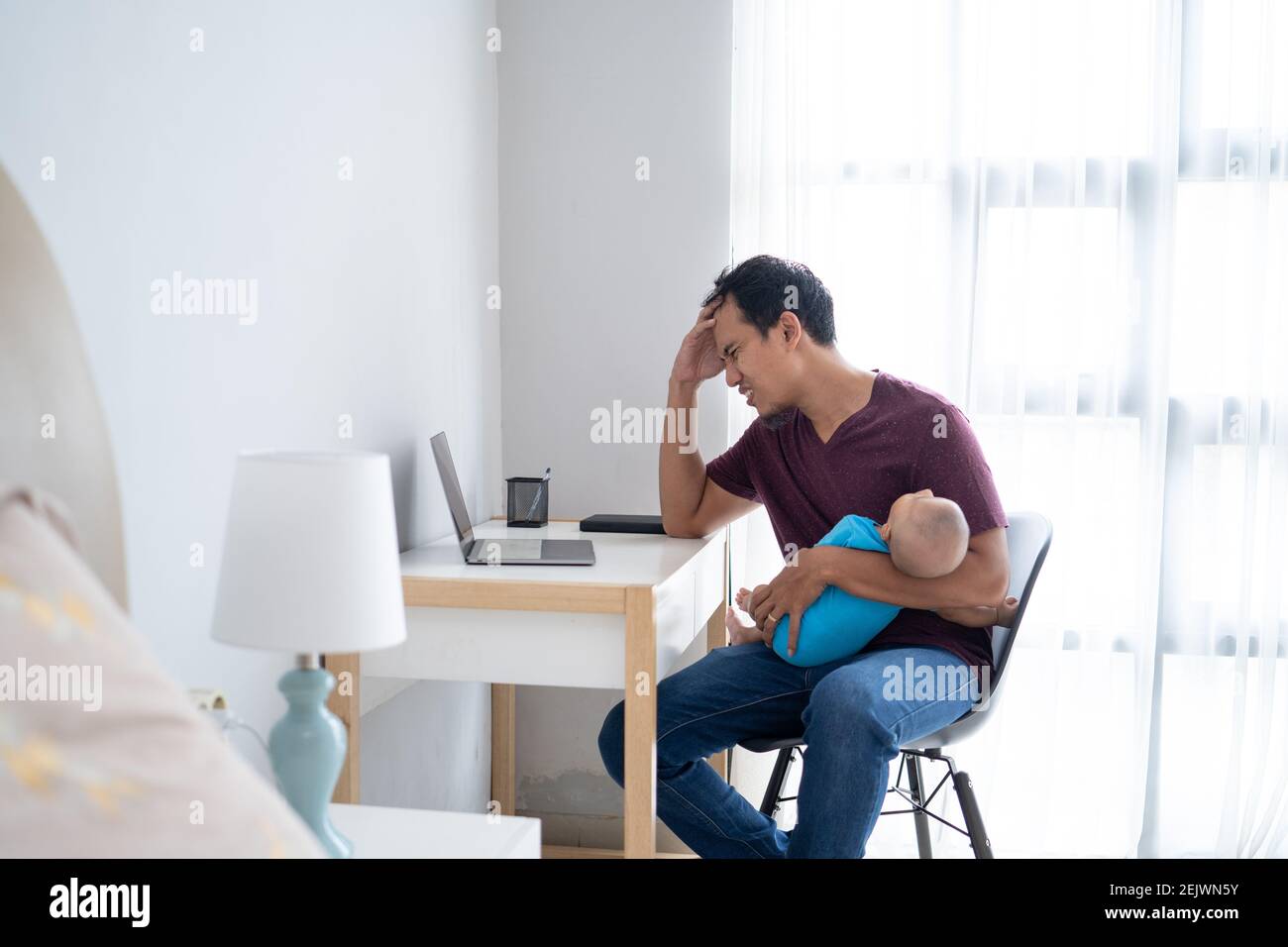 portrait of a stress busy father working from home while holding his ...
