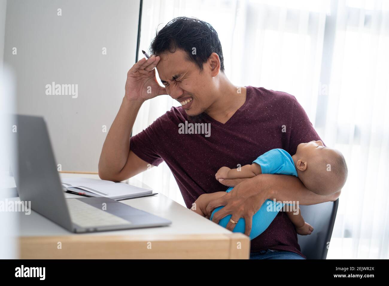 portrait of a stress busy father working from home while holding his ...