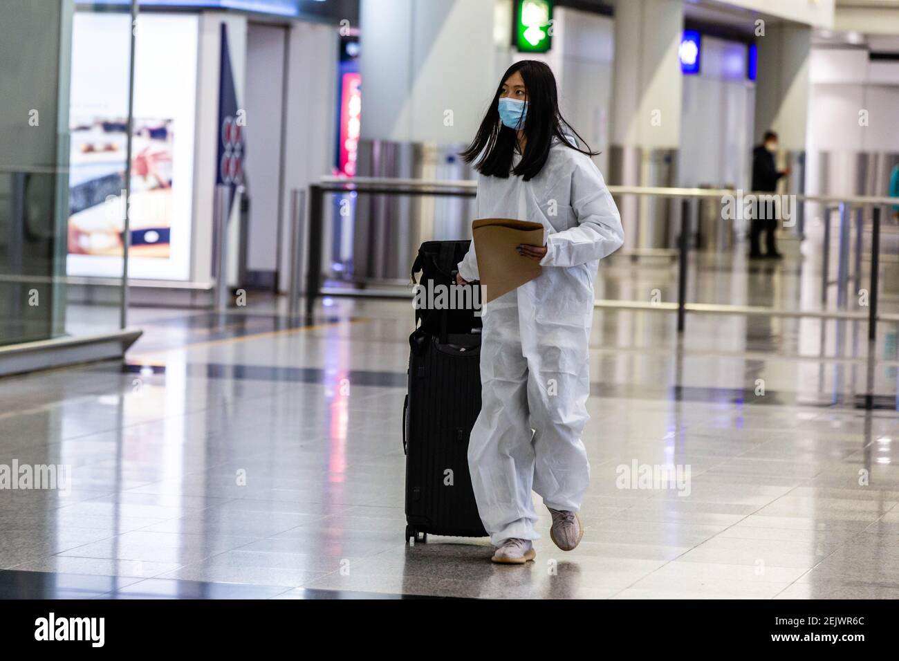 A masked passenger wearing a protective white robe as preventive ...