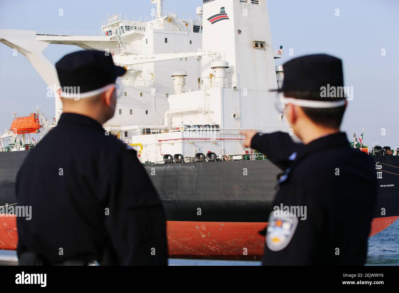 Police officers patrol outside the ship unloading crude oil, Qingdao ...