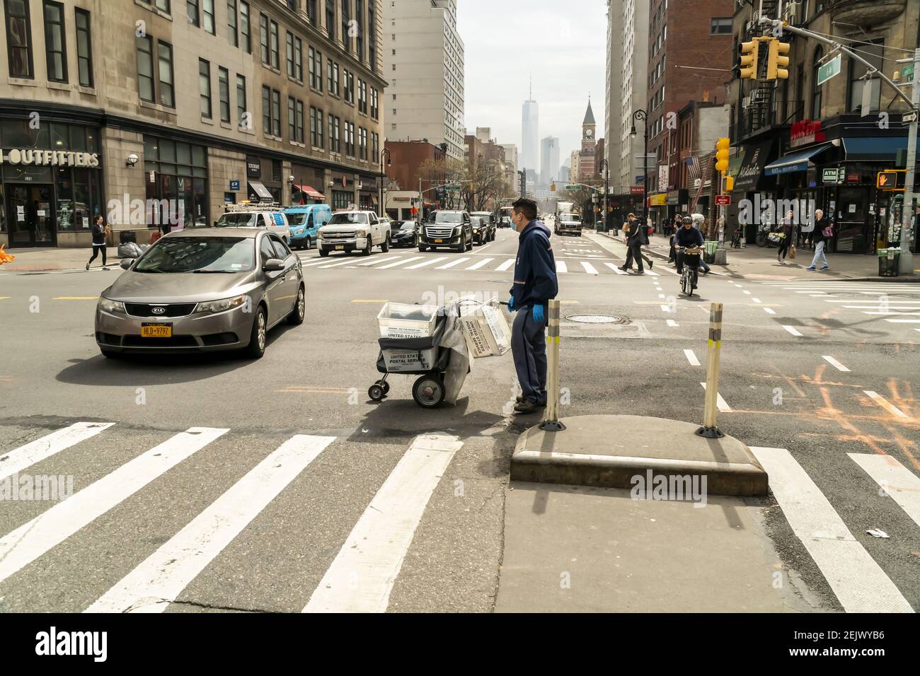A masked USPS mail carrier crosses Sixth Avenue in New York on Friday ...
