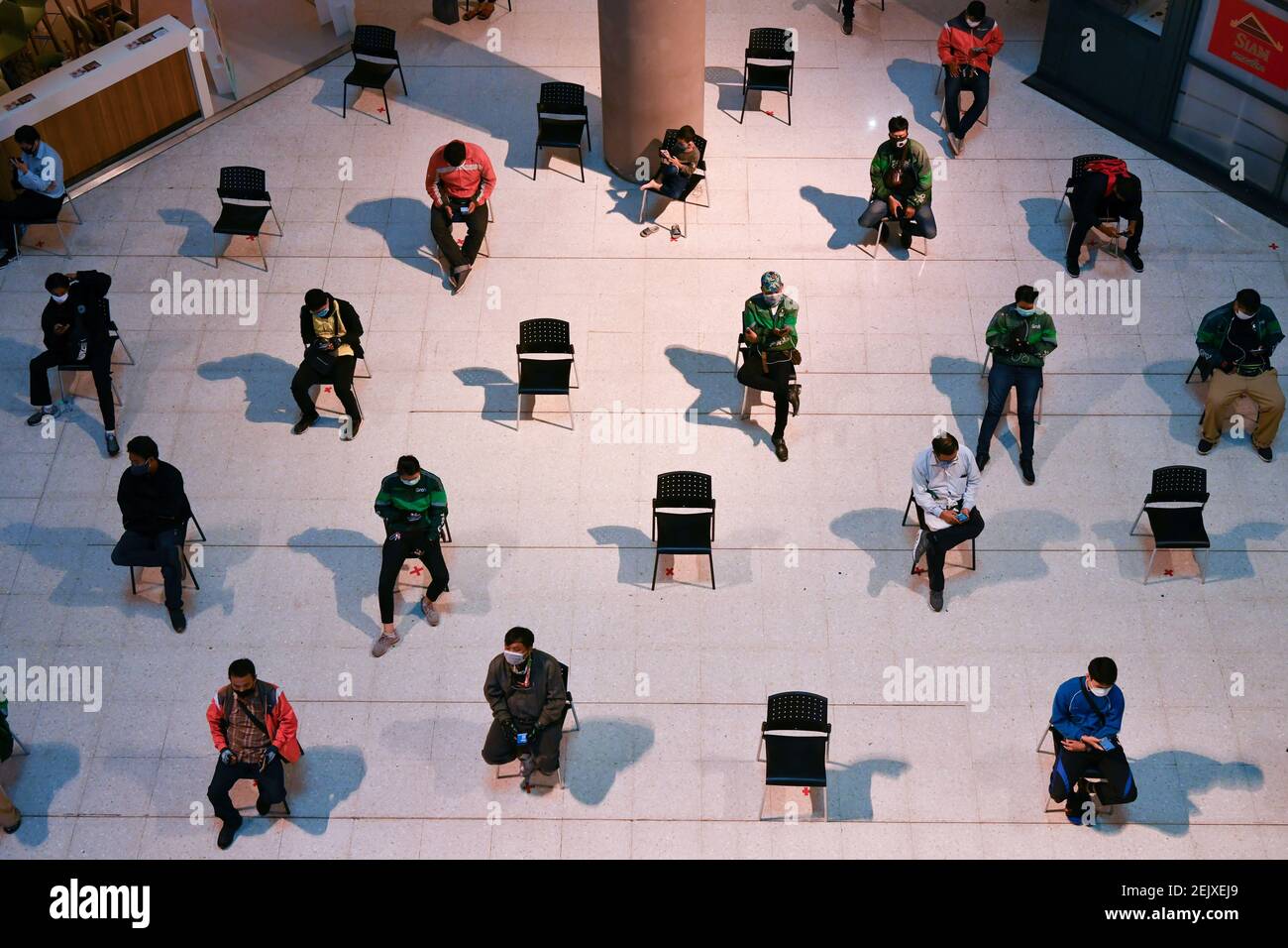 People practice social distancing as they sit on chairs spread apart in ...