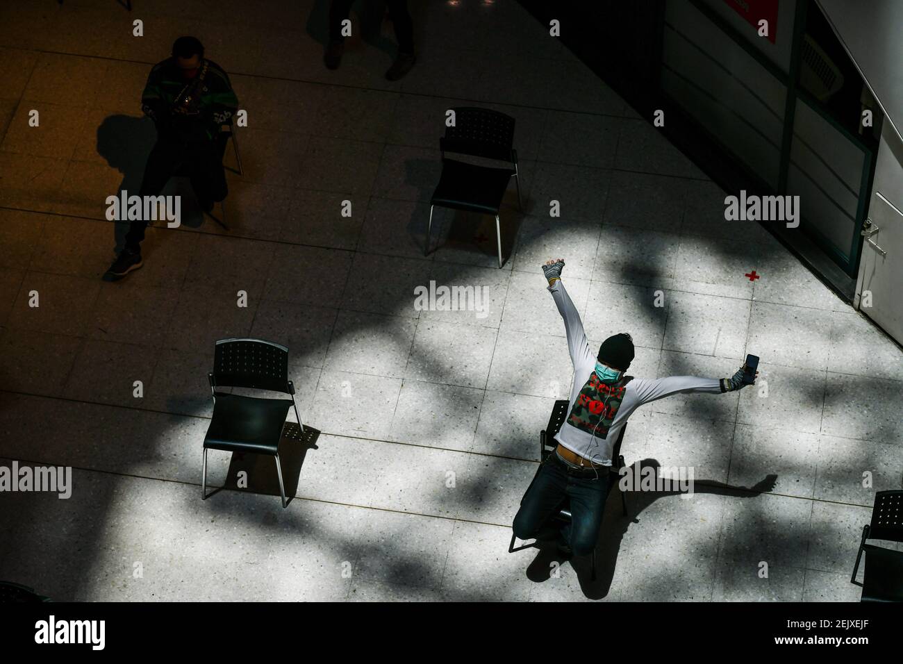 People practice social distancing as they sit on chairs spread apart in ...