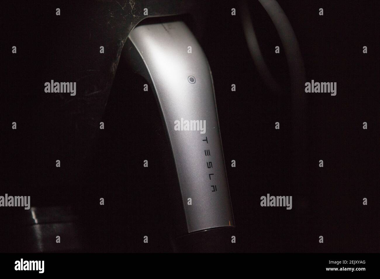 In this photo illustration, a Tesla logo seen on a charging plug of a ...