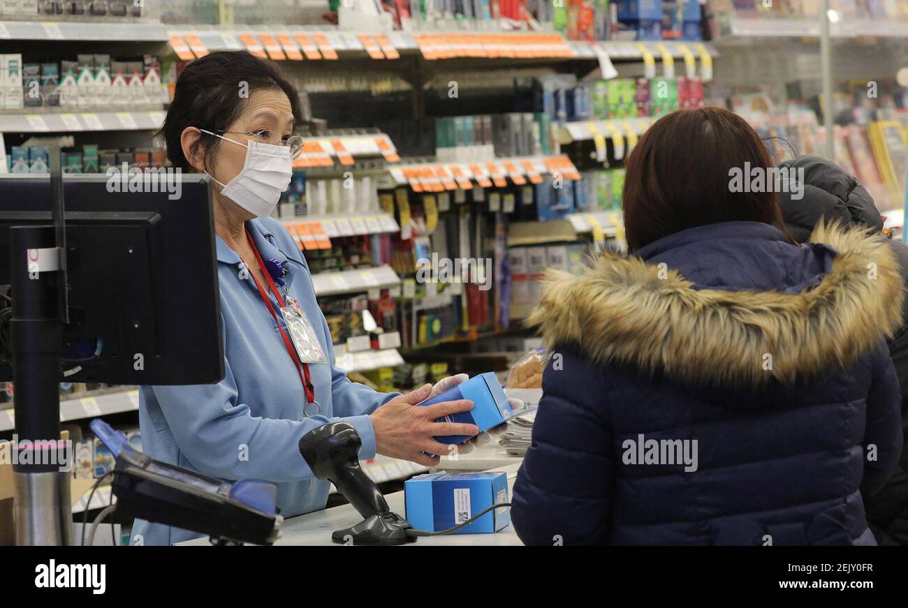 A sales clerk at Walgreens rings up a purchase of surgical face masks ...