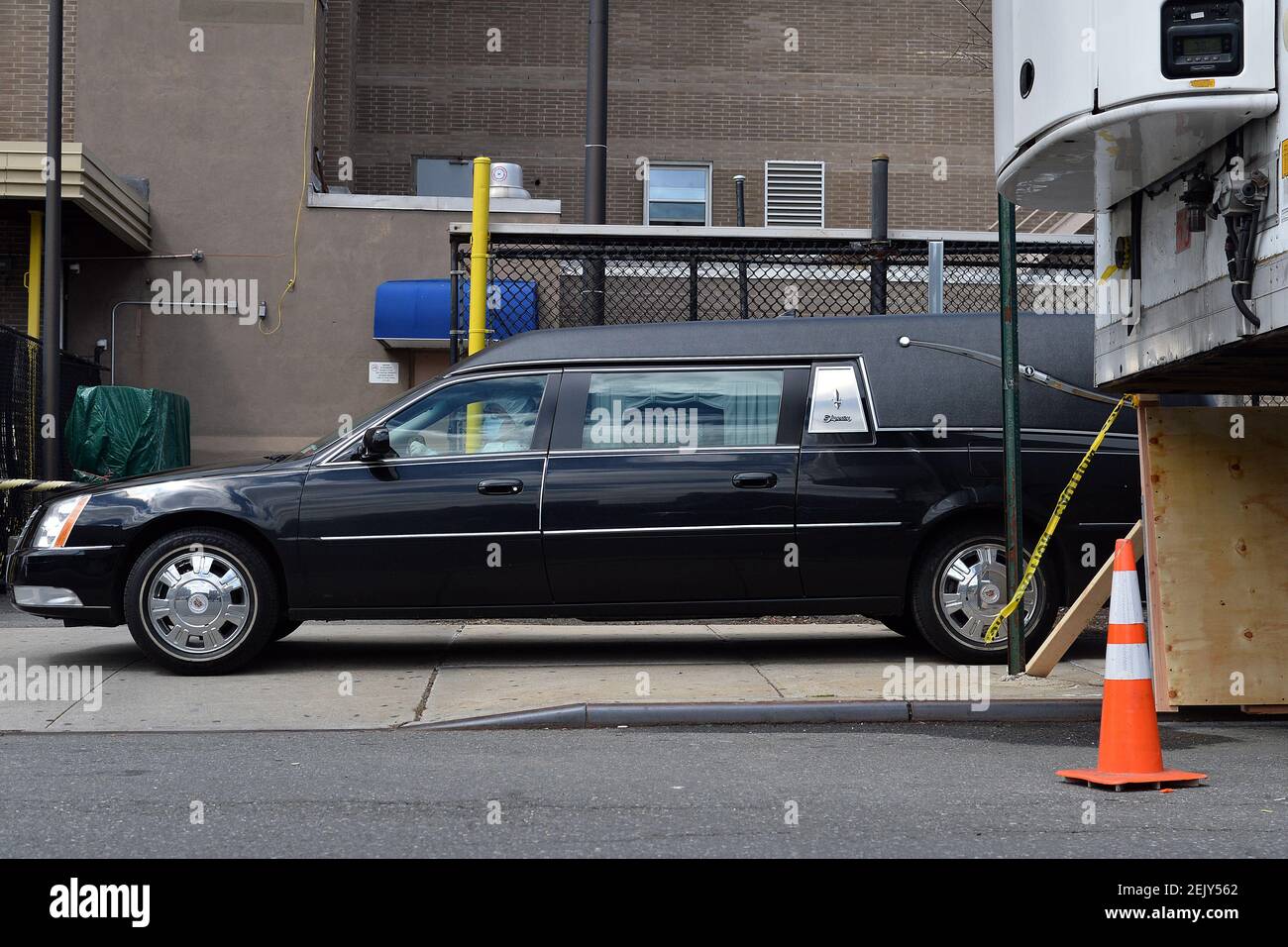 A hearse driver wearing protective medical clothing is seen backing up ...