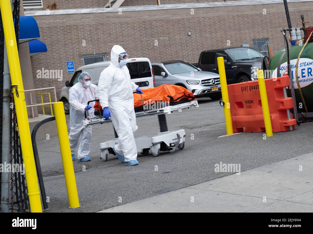 Hospital workers are seen transporting a body to a portable morgue ...