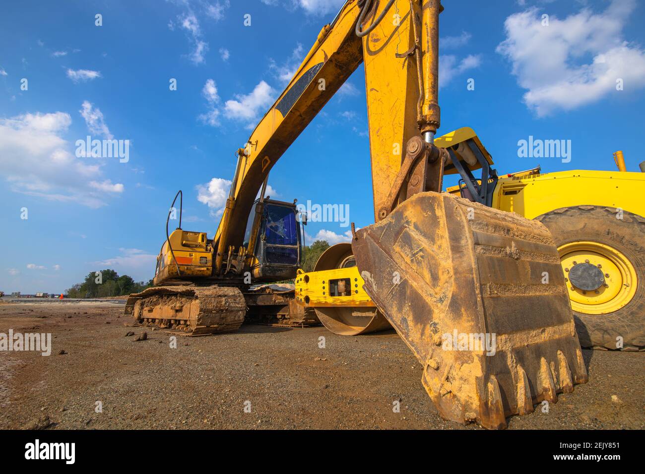 Backhoe and road roller on the ground at site construction Stock Photo ...