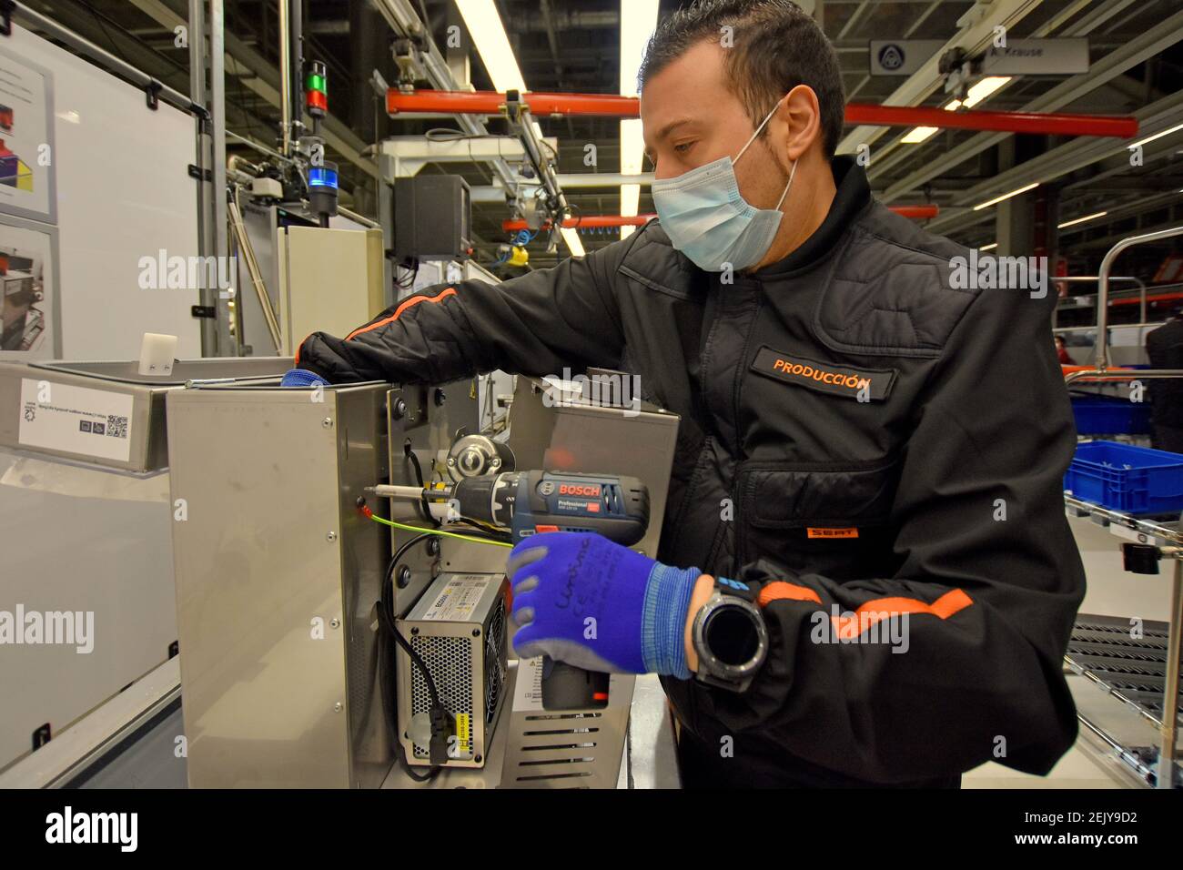 A male assembly operator protected with a surgical mask and gloves ...