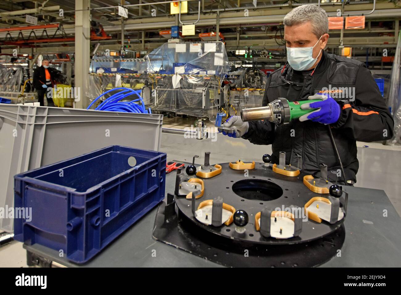 A male assembly operator protected with a surgical mask and gloves ...