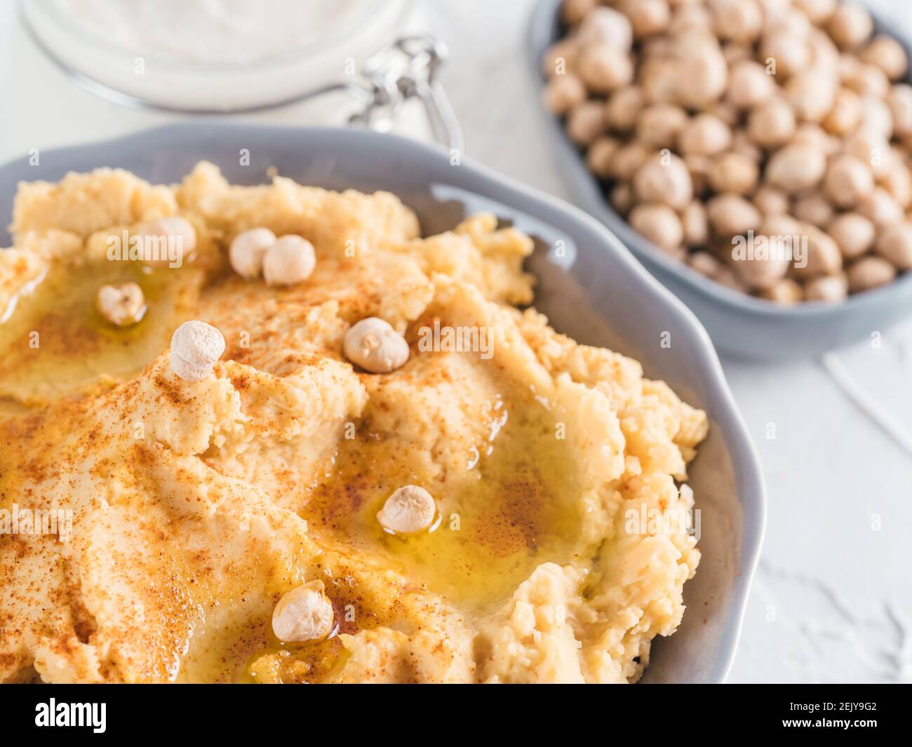Homemade hummus with olive oil in gray bowl and tahini. Traditional ...