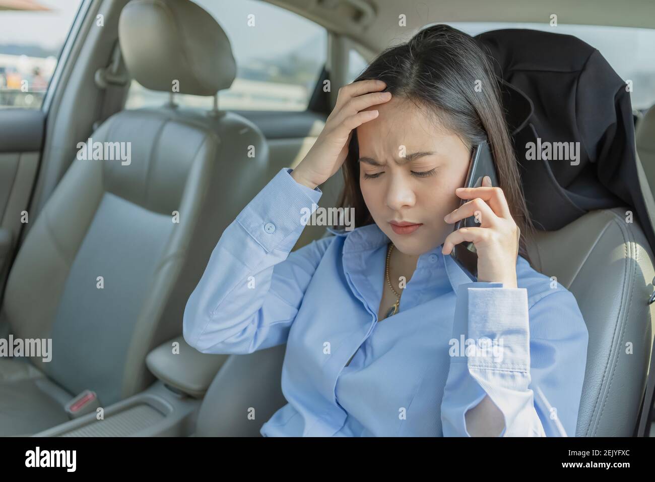 Businesswoman inside a car using a mobile phone for working and she is ...