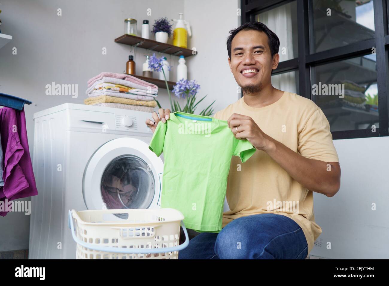 Housework. asian Man doing laundry at home loading clothes into washing ...