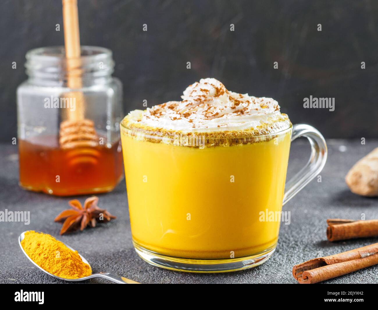 Healthy drink golden turmeric latte with whipped cream in glass cup ...