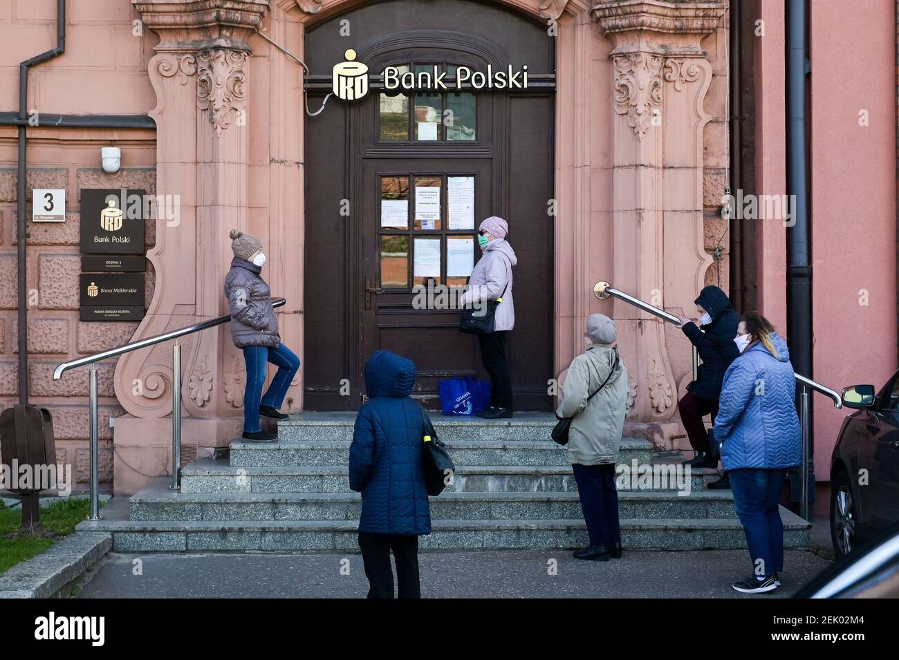 People await in front of Bank Polski while wearing protective masks as ...