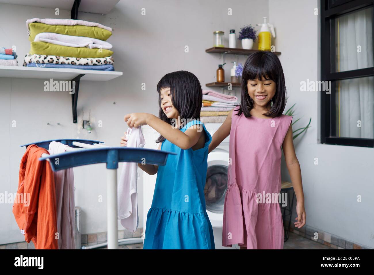 two children having fun happy little girl to wash clothes and laughs in ...