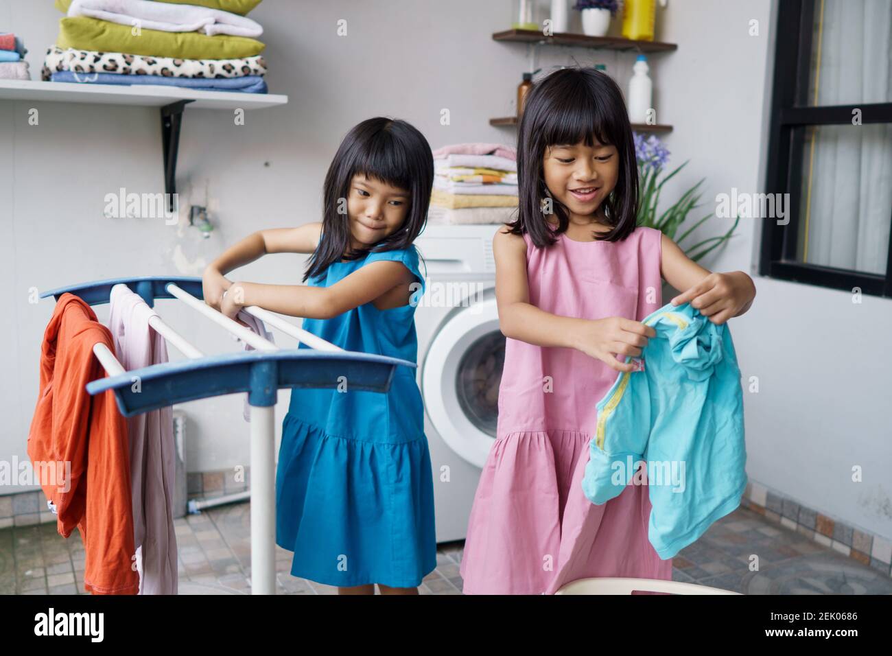 two children having fun happy little girl to wash clothes and laughs in ...