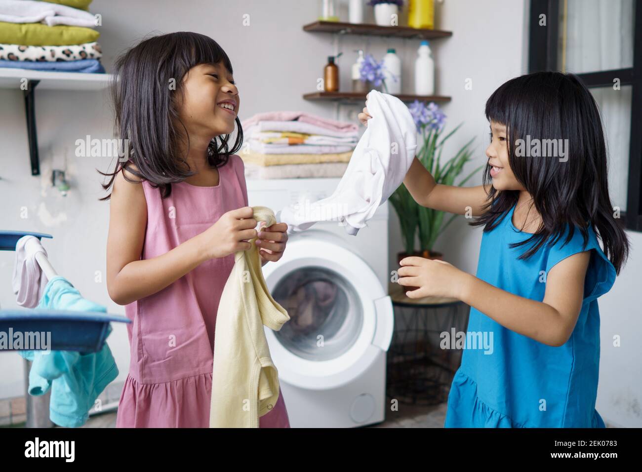 two children having fun happy little girl to wash clothes and laughs in ...