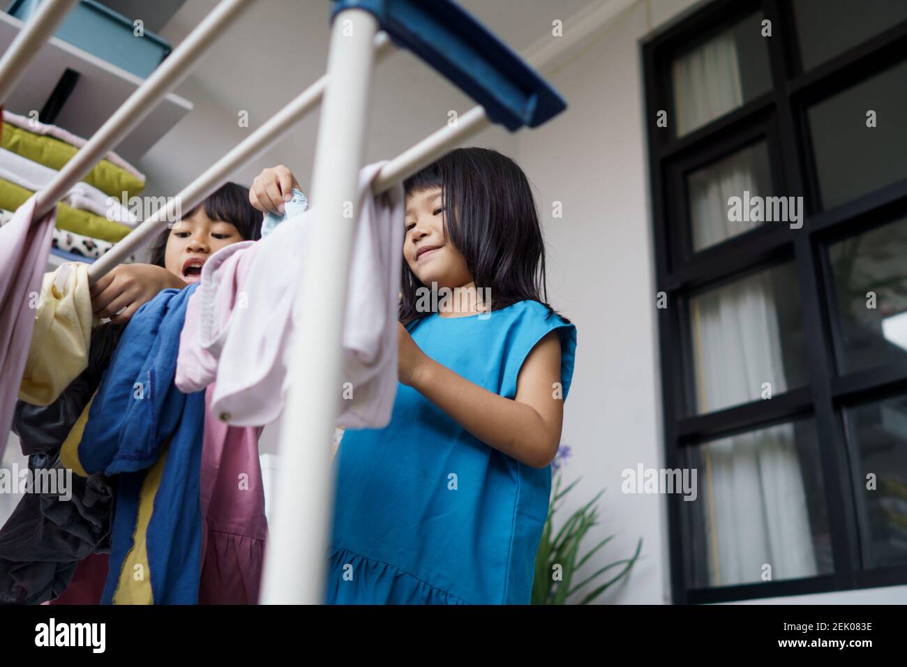 two children having fun happy little girl to wash clothes and laughs in ...