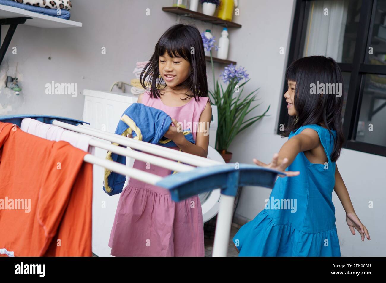 two children having fun happy little girl to wash clothes and laughs in ...