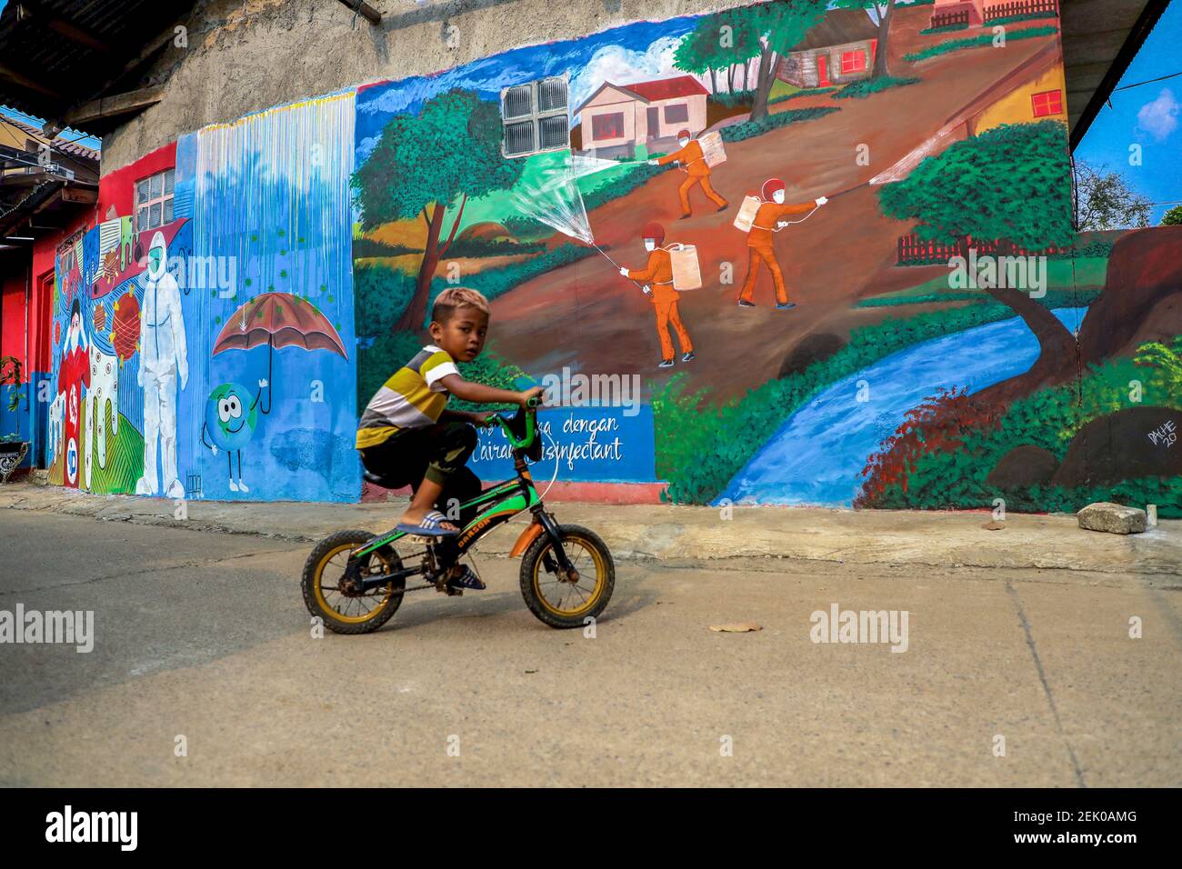 A child rides a bicycle past a coronavirus awareness graffiti during a ...