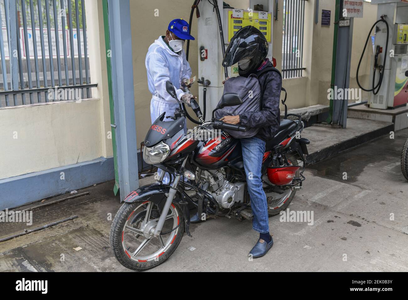 An employee wearing a personal protective equipment (PPE) fills up a ...