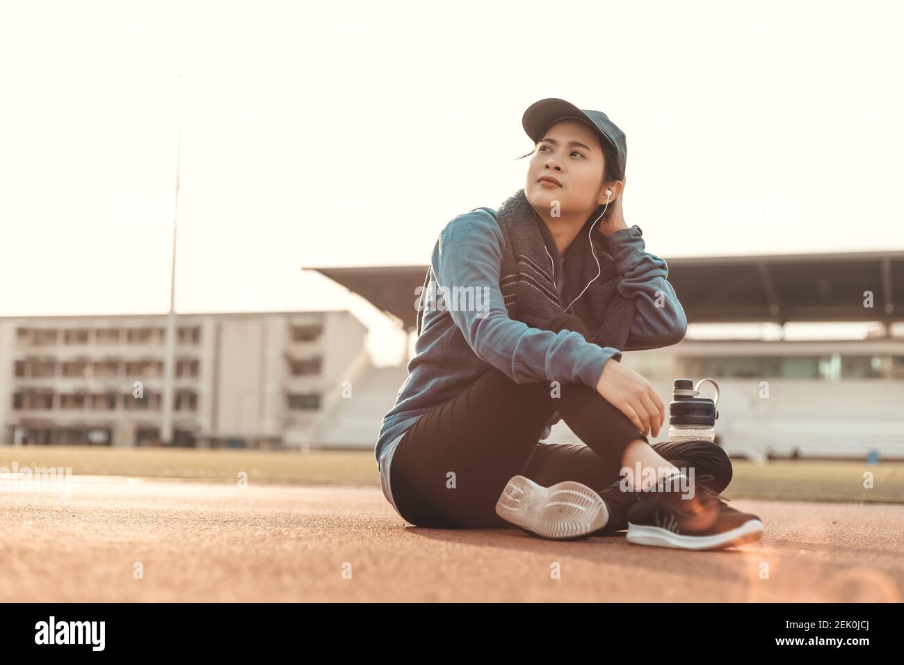 woman athlete thirsty takes a break. she sitting on the track race and ...