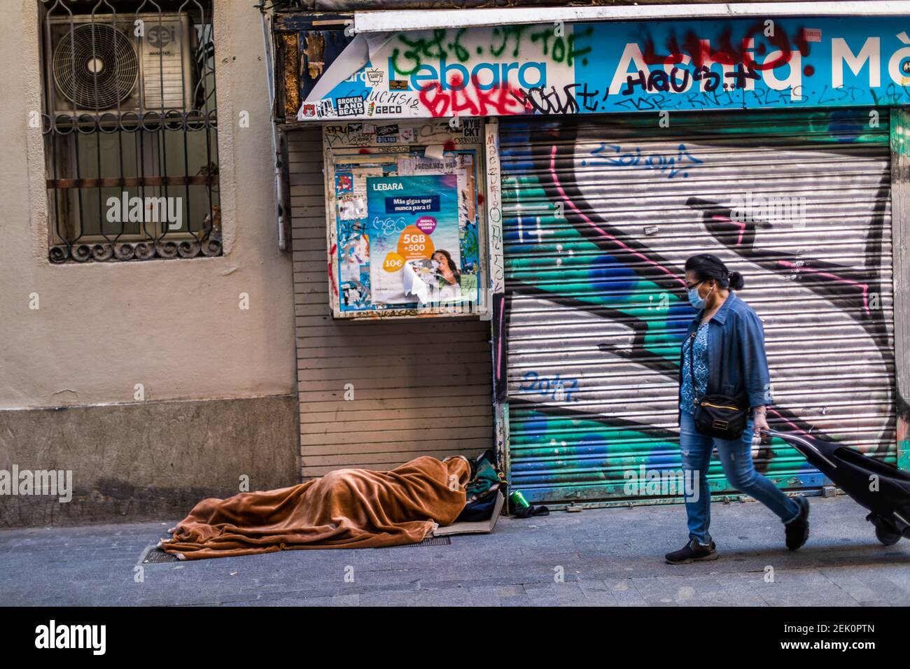 A woman wearing a face mask as a precaution, walks past a homeless ...