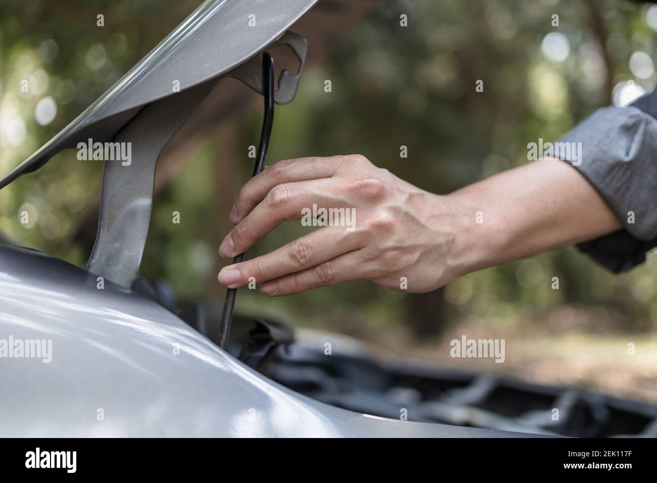 Man' hand open hood of a broken car on the road in the forest. Car ...