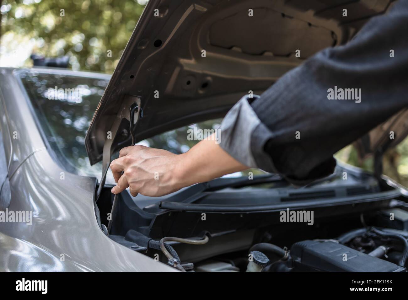 Man' hand open hood of a broken car on the road in the forest. Car ...