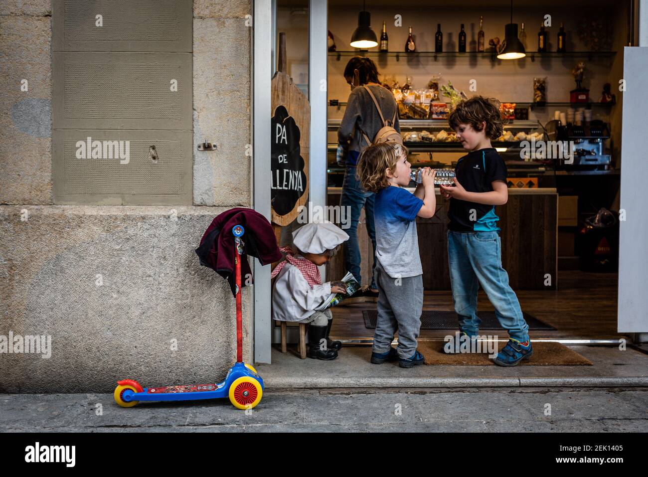 Two kids waiting for their mum outside the open El Pont de Ferro bakery ...