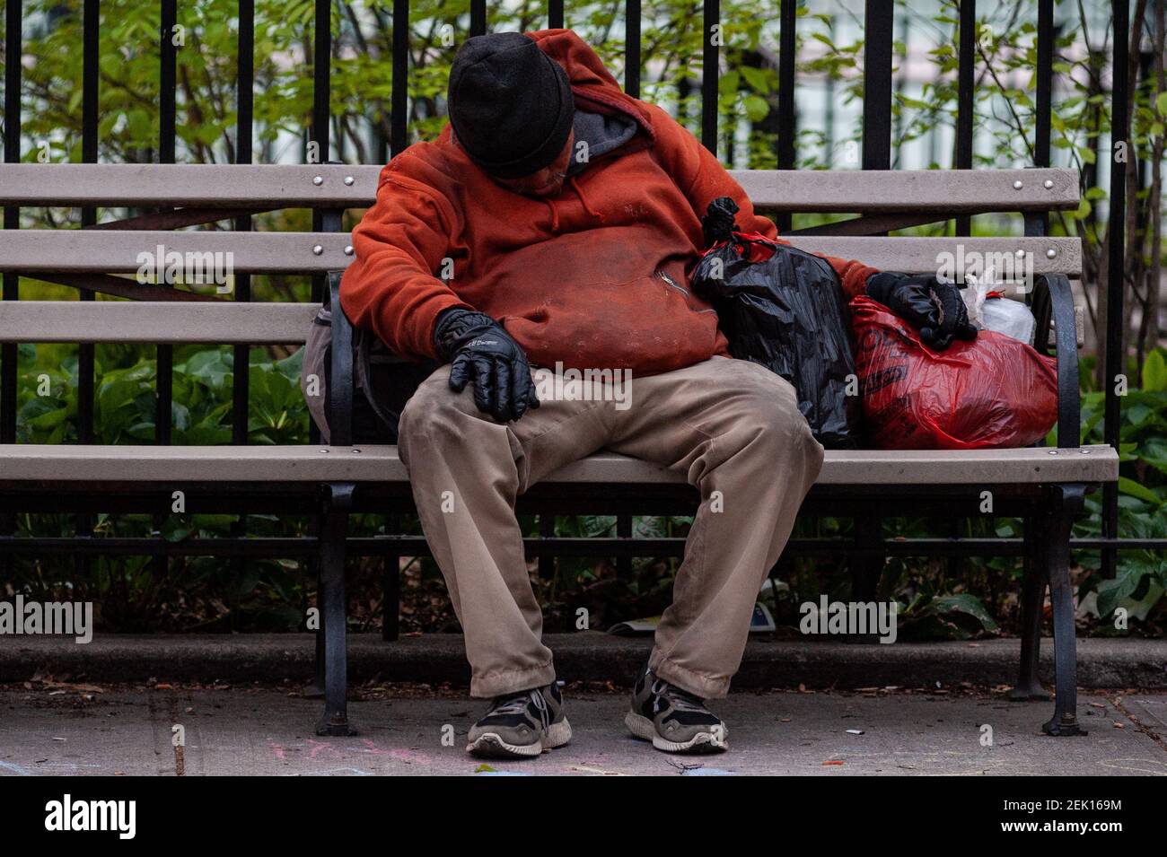 A homeless person rests on a park bench in the Park Slope neighborhood ...