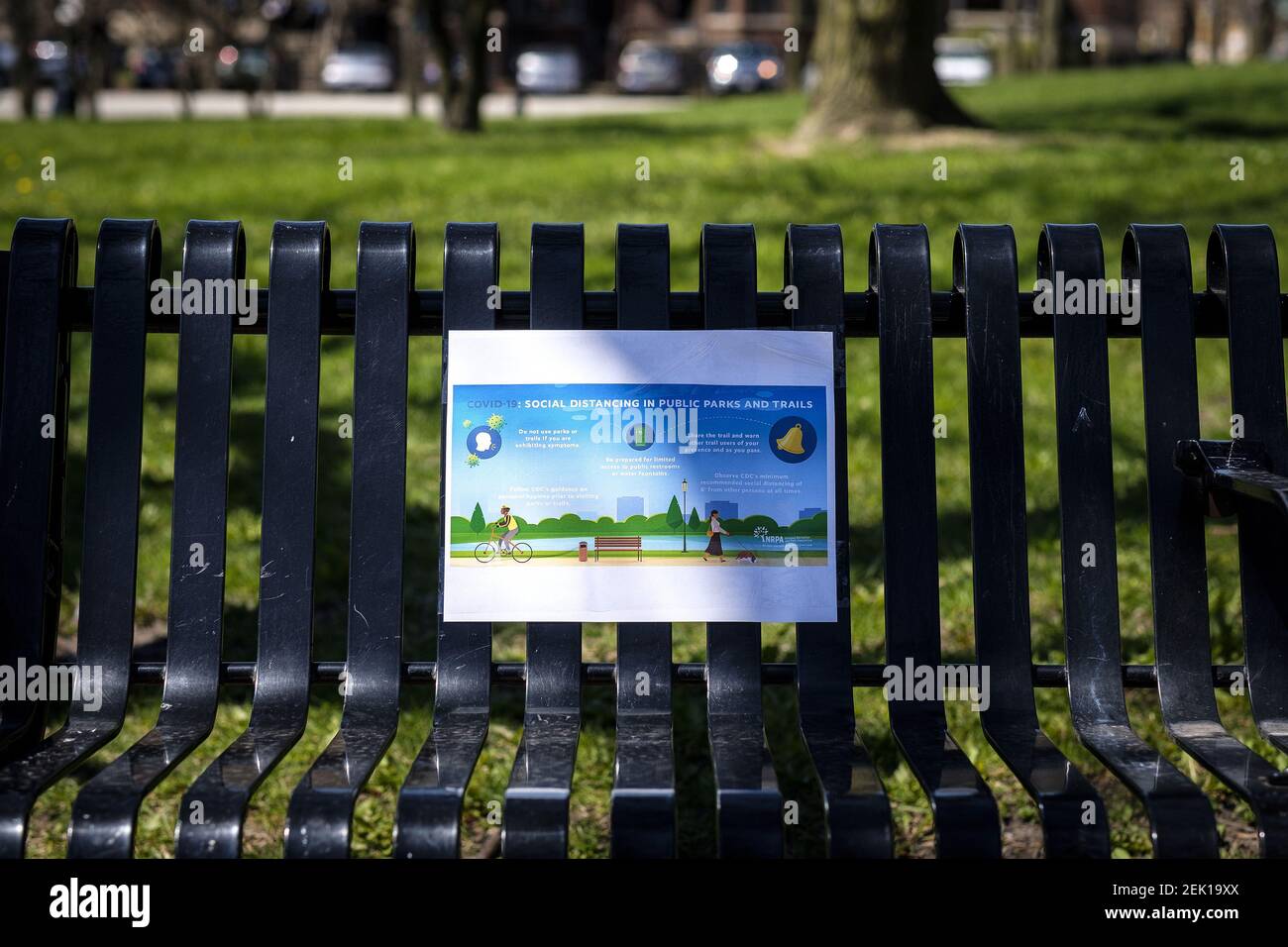 A sign on a park bench explains social distancing in public spaces in ...