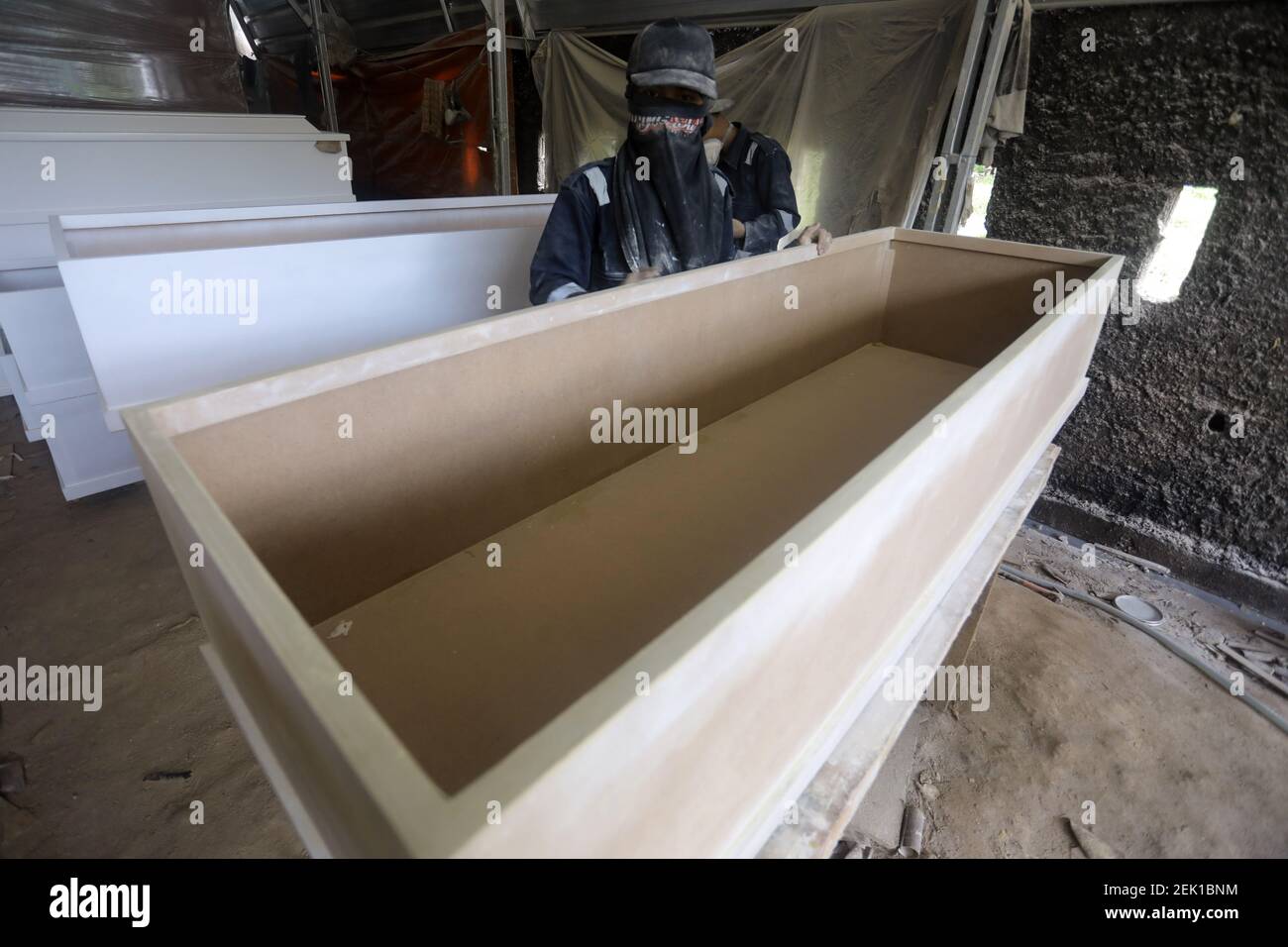 A coffin maker working on special coffins coated with plastic to ...