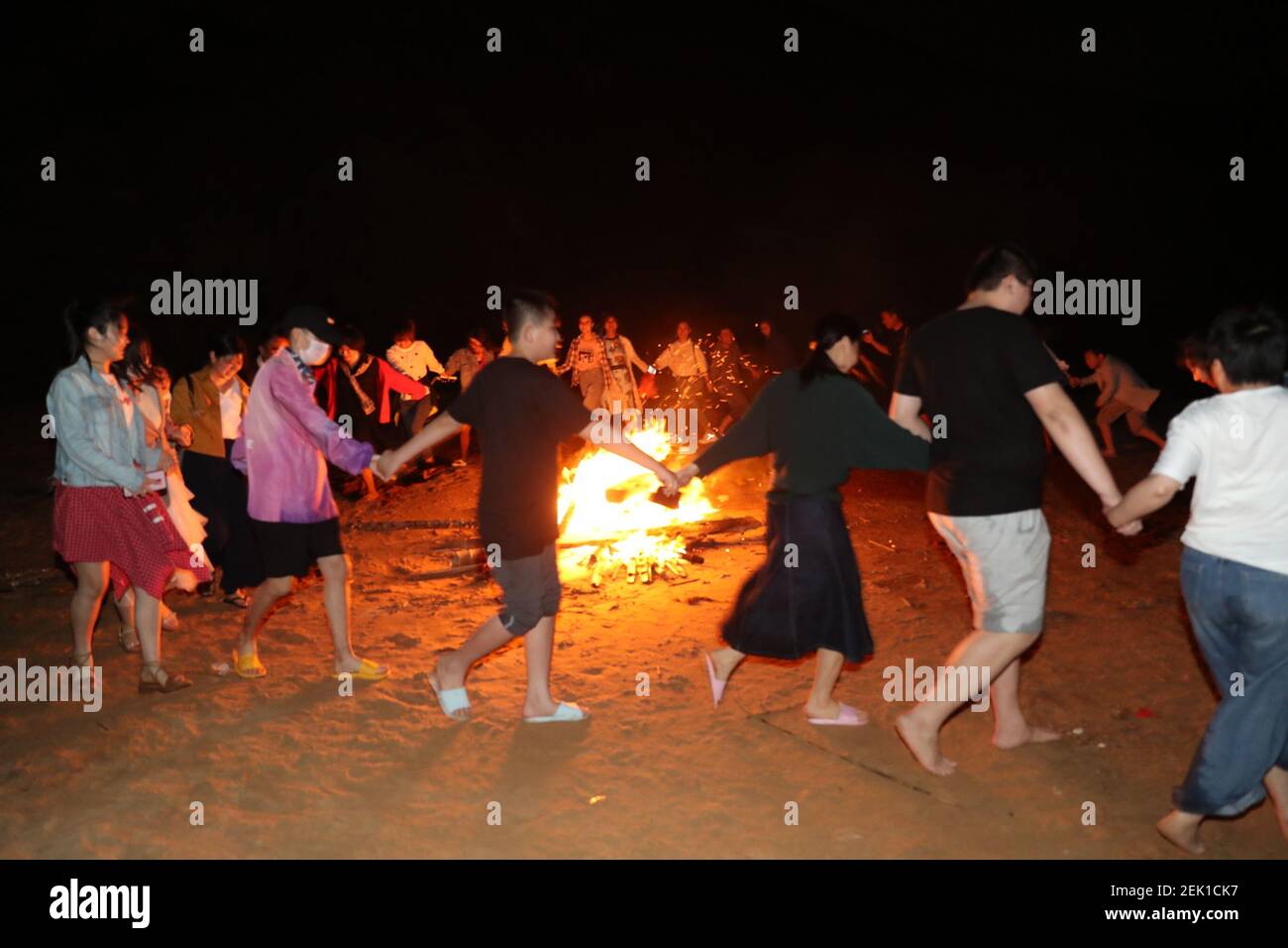 Tourists dance with local people around bonfire, waiting for the ...