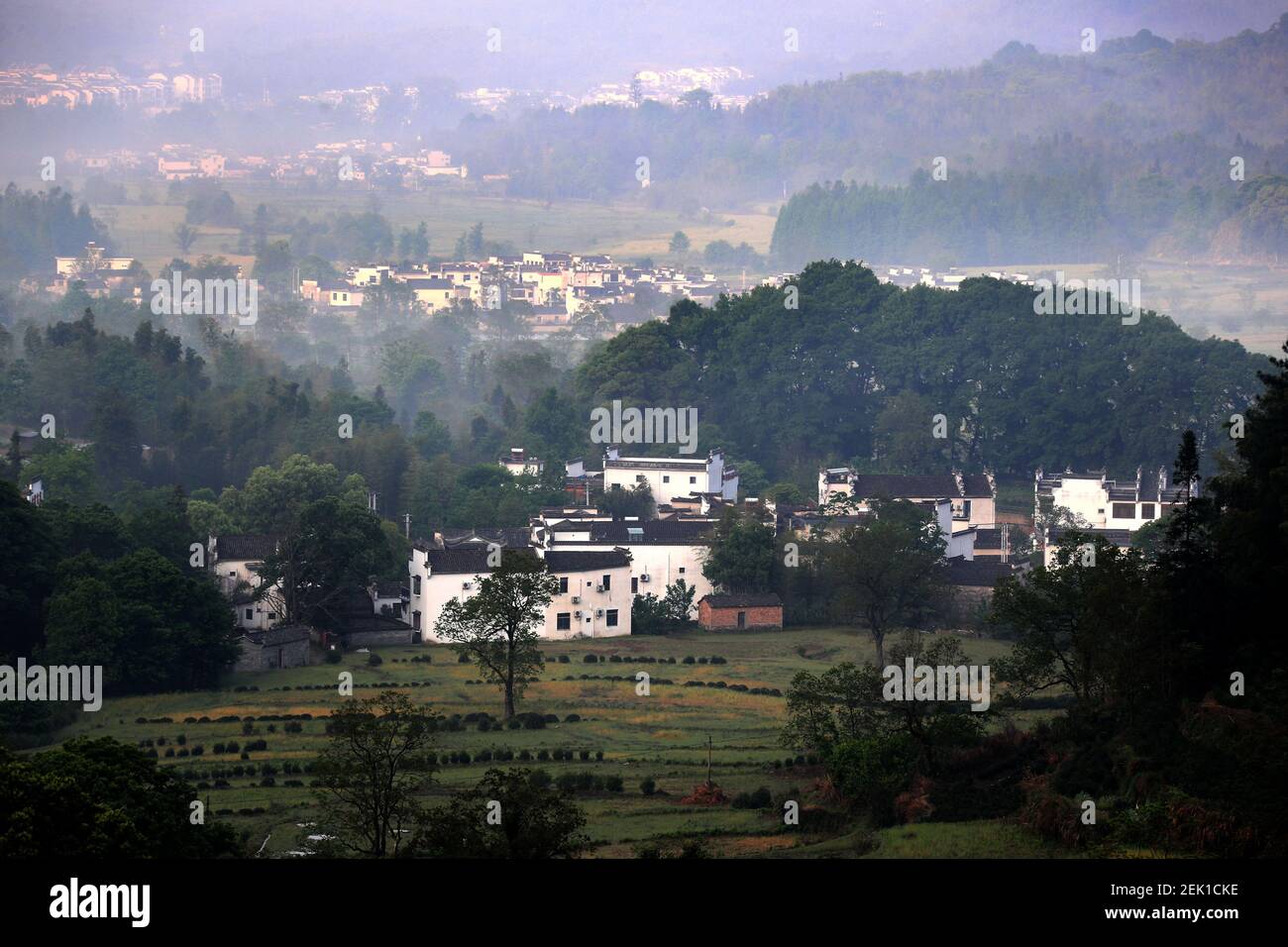 An aerial view of Hui-style buildings scattering near woods in the mist ...
