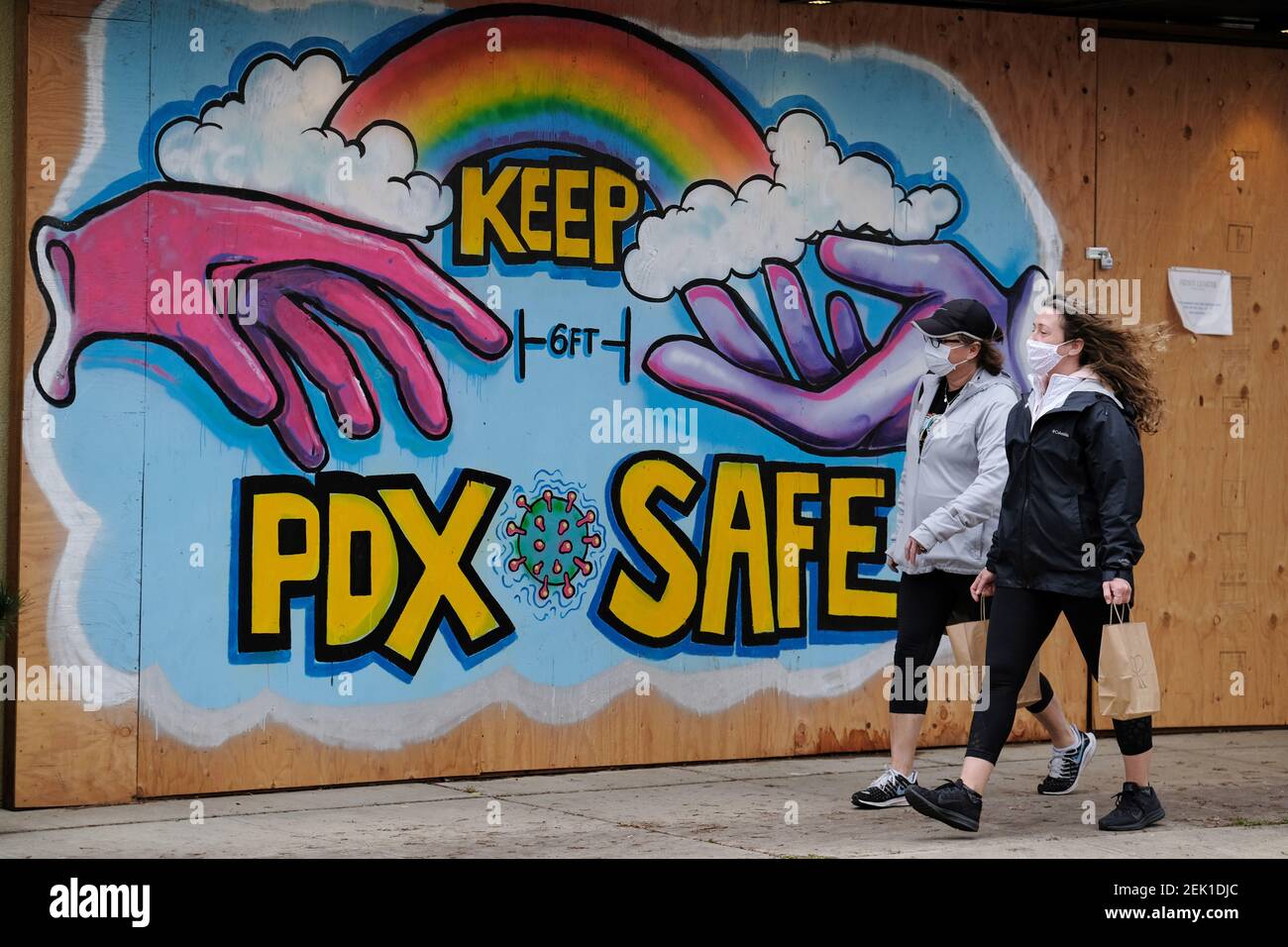 Women wearing face masks walk past social distancing street art by ...