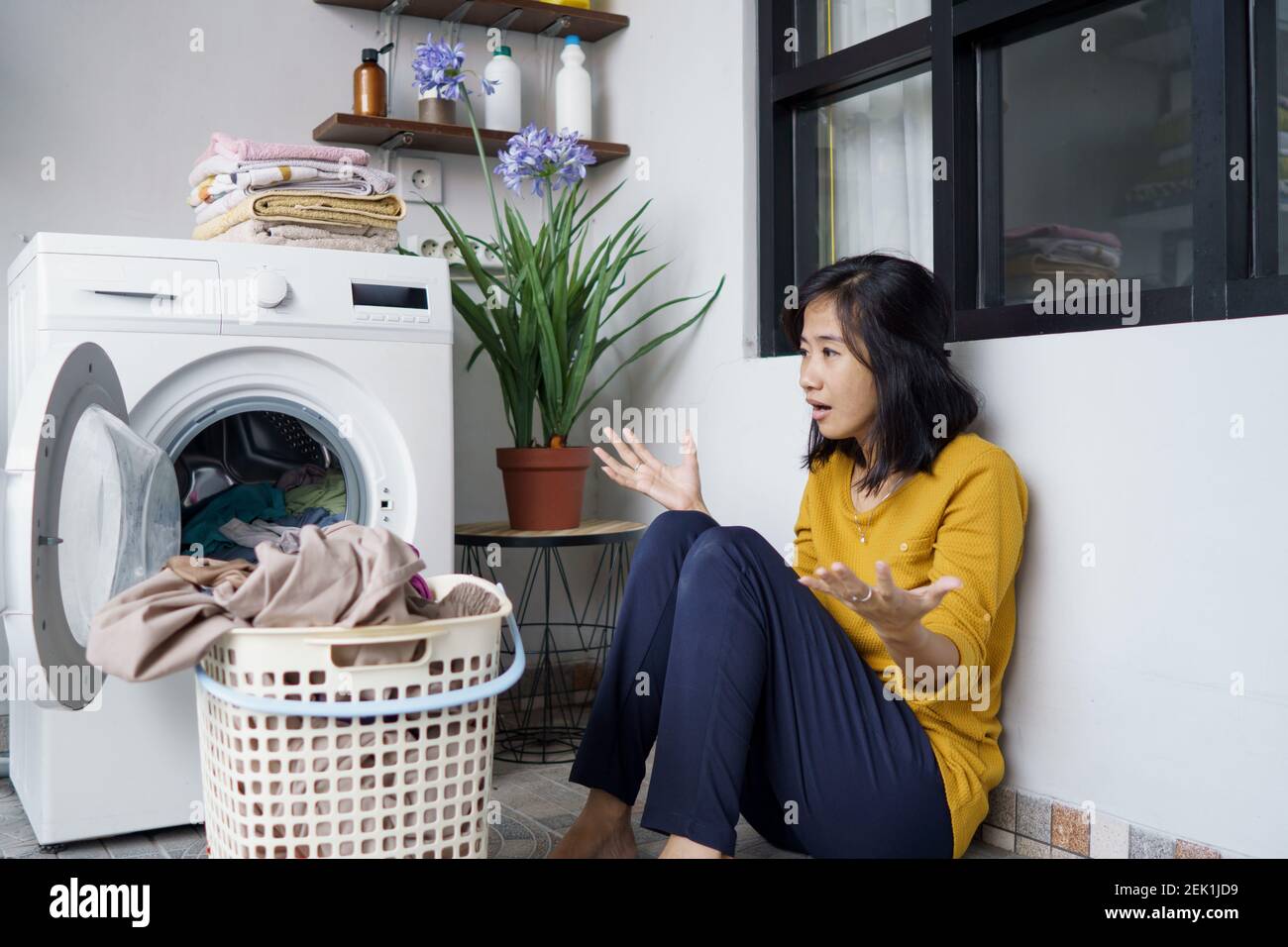 stressed pretty asian housewife doing some laundry at home Stock Photo ...