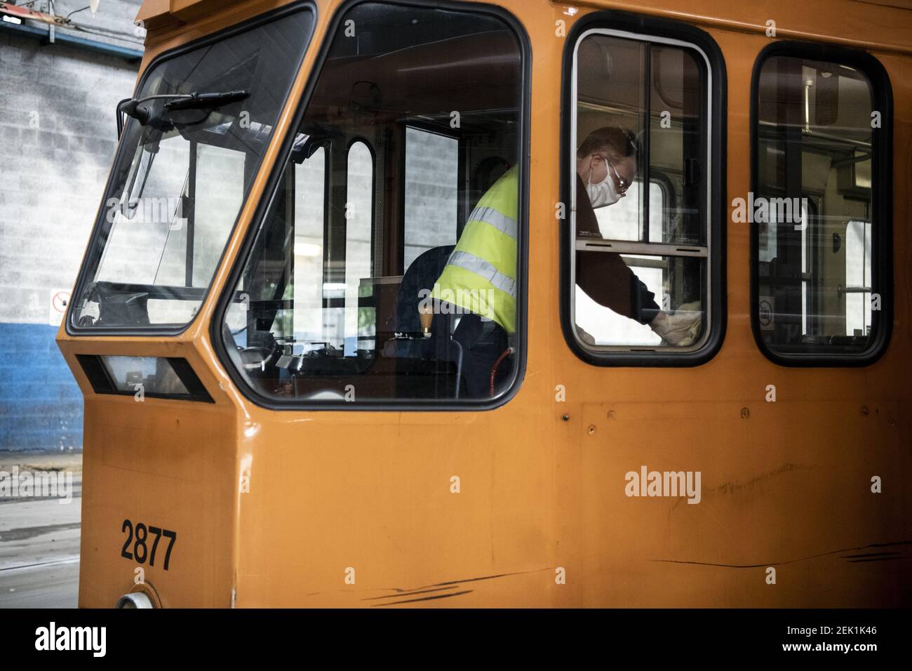 A technician, wearing protective mask, cleaning bus and tram during ...