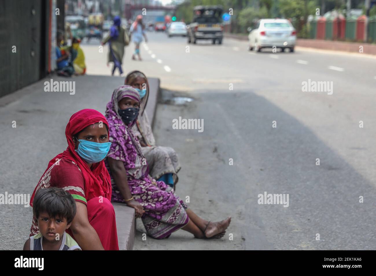 Homeless people wait for relief at the road side while wearing face ...