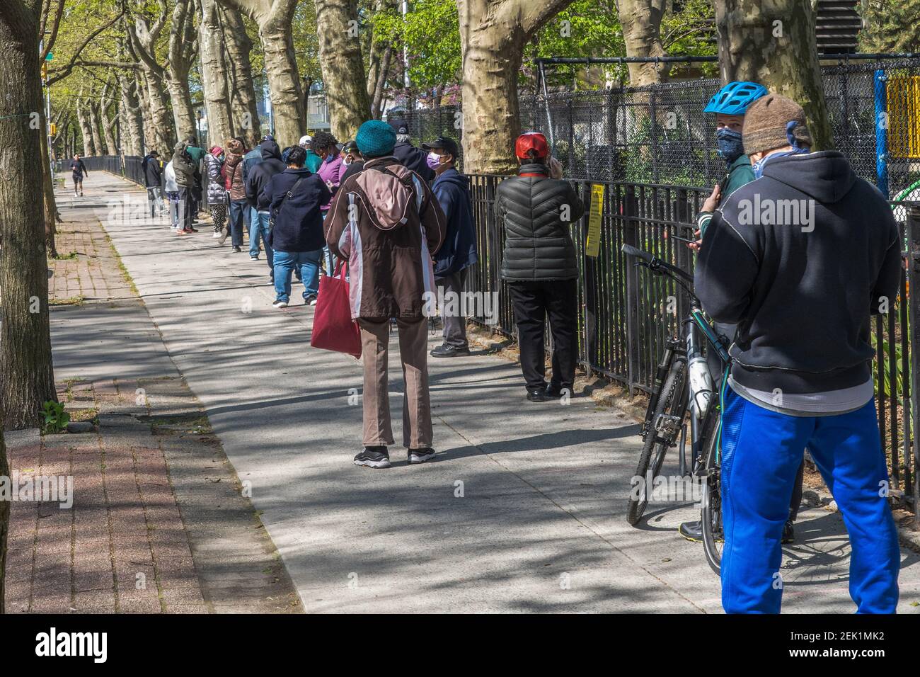 People queue at a social distance for free face masks at the ...