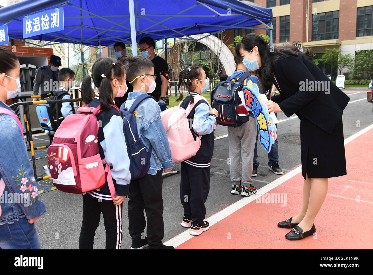 A school staff greets students by the gate of Hefei Normal University ...