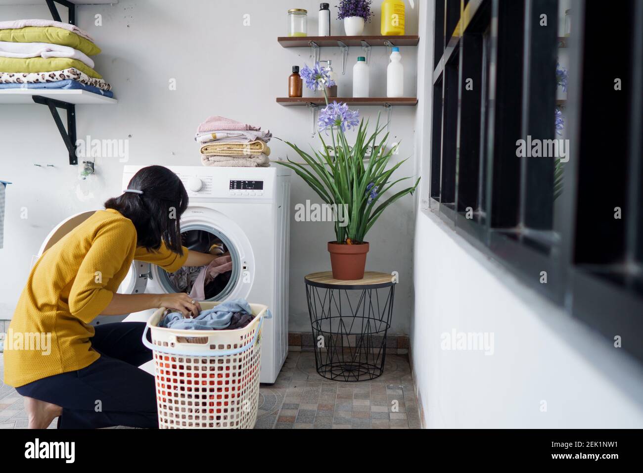 woman in front of the washing machine doing some laundry loading ...